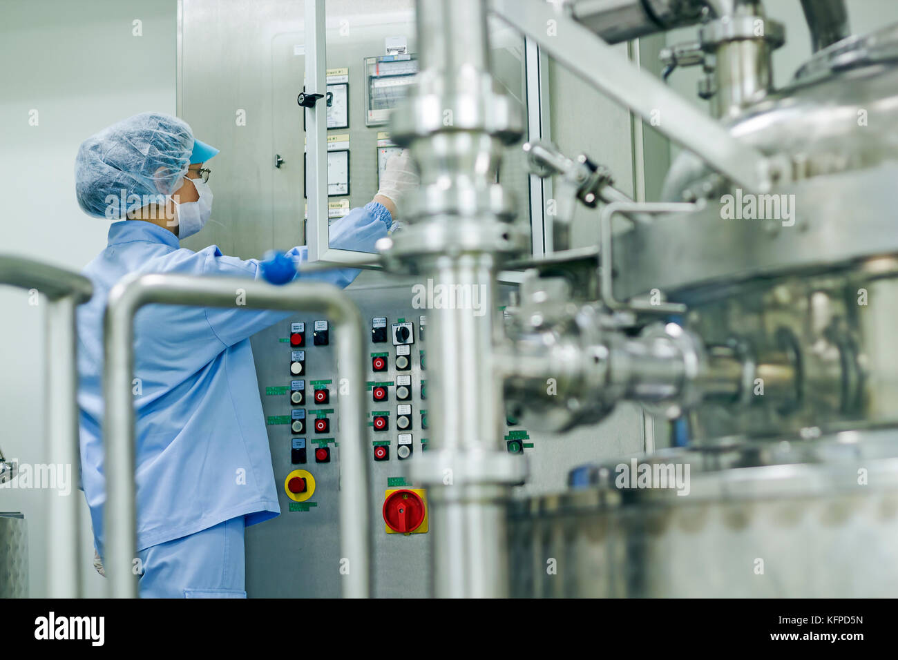 Female worker at pharmaceutical factory operating control panel of the ...