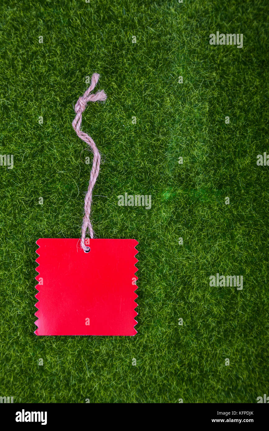Red tag on a green grass close-up Stock Photo - Alamy