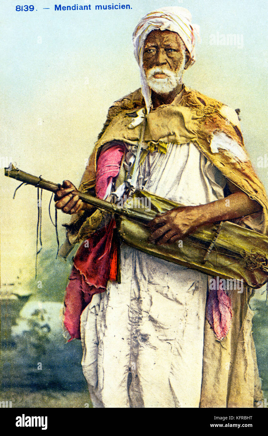 Travelling North African musician holding an instrument. A gimbri or ...