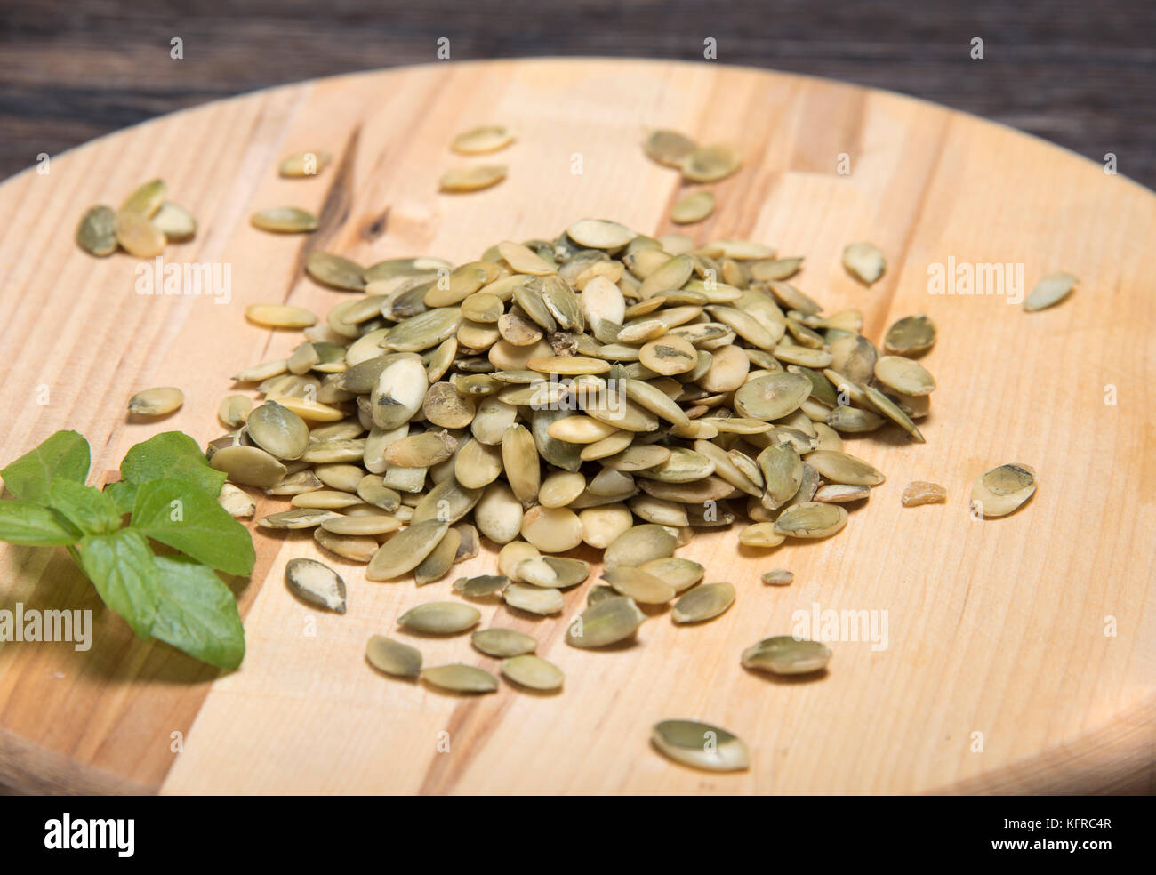 pumpkin seeds and basil leaves round cutting board close up Stock Photo ...