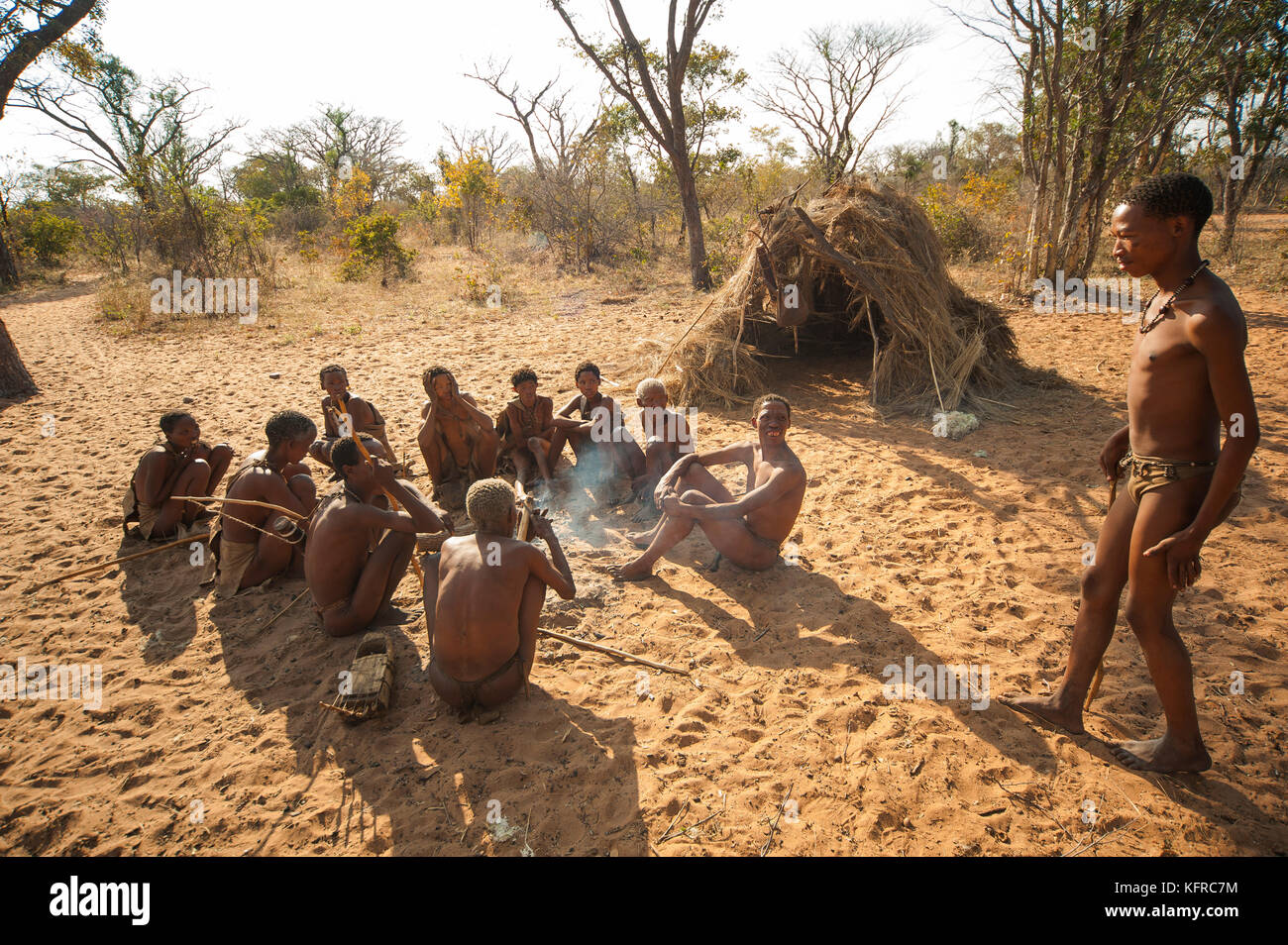 Ju/'Hoansi or San bushmen hunter gathering around camp fire at their ...