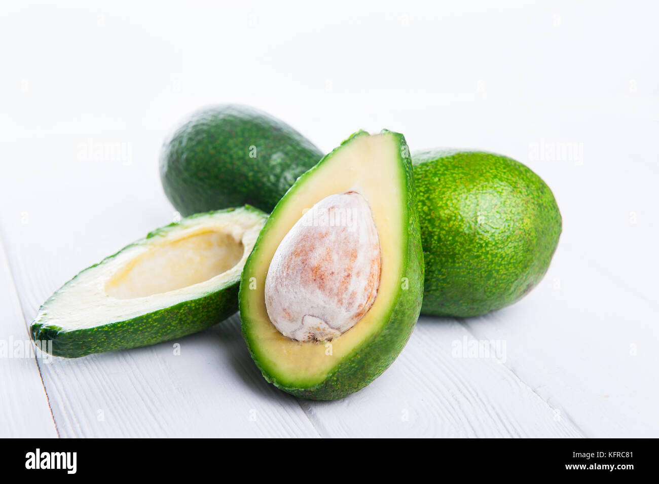Close up Few whole avocados and cuted one on the white wooden table ...