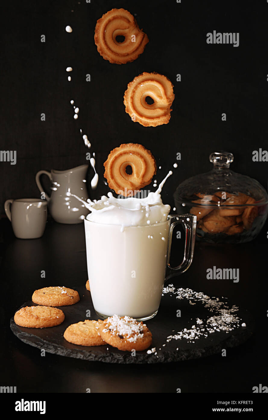 Milk splash. Falling cookies to glass of milk with splash on black ...