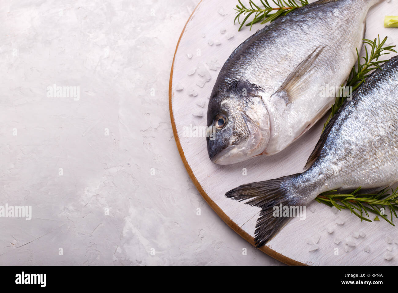 Raw sea bream fish with rosemary and broccoli on white gray stone ...