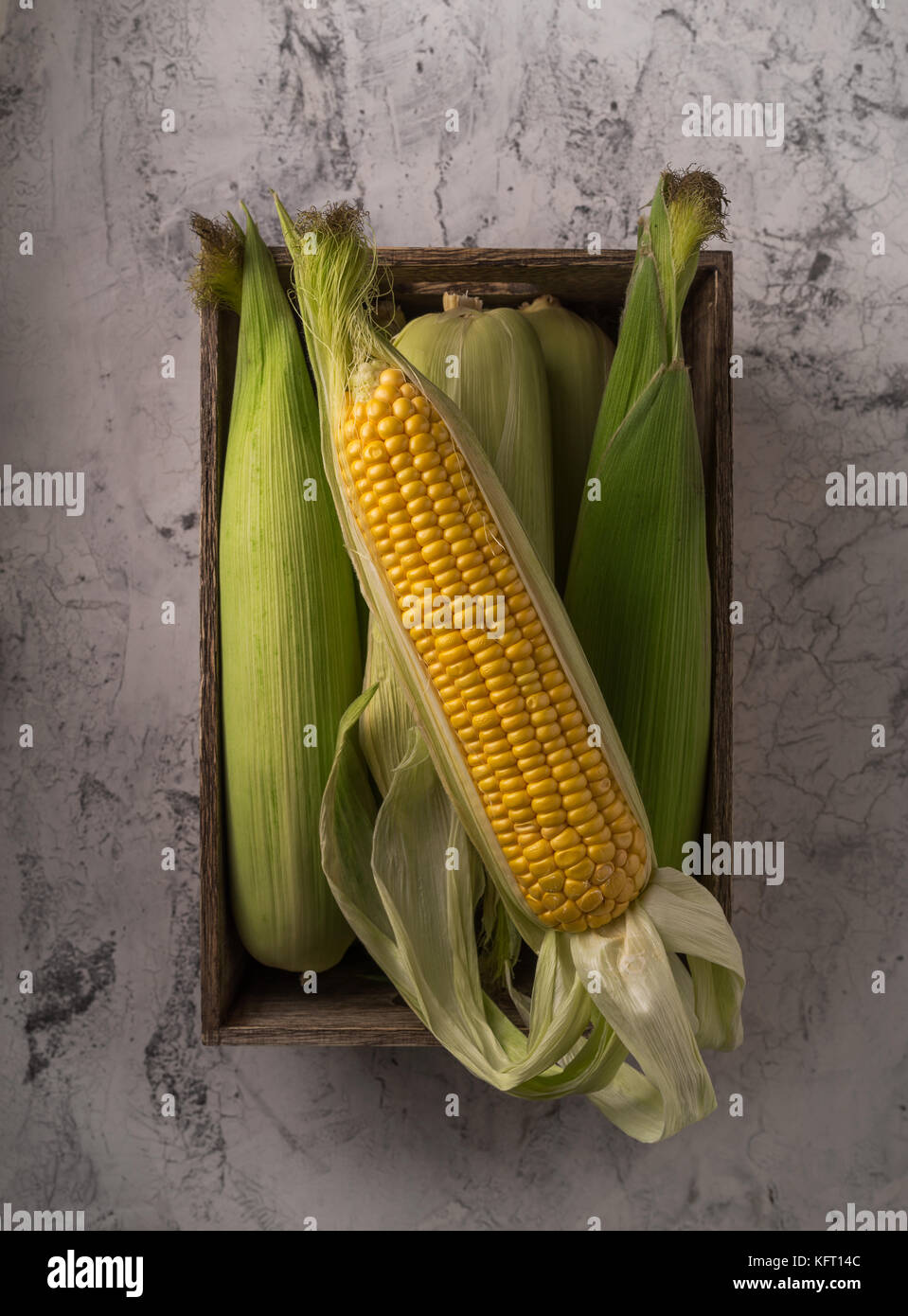 Box full of fresh corn cobs on the old concrete Stock Photo - Alamy