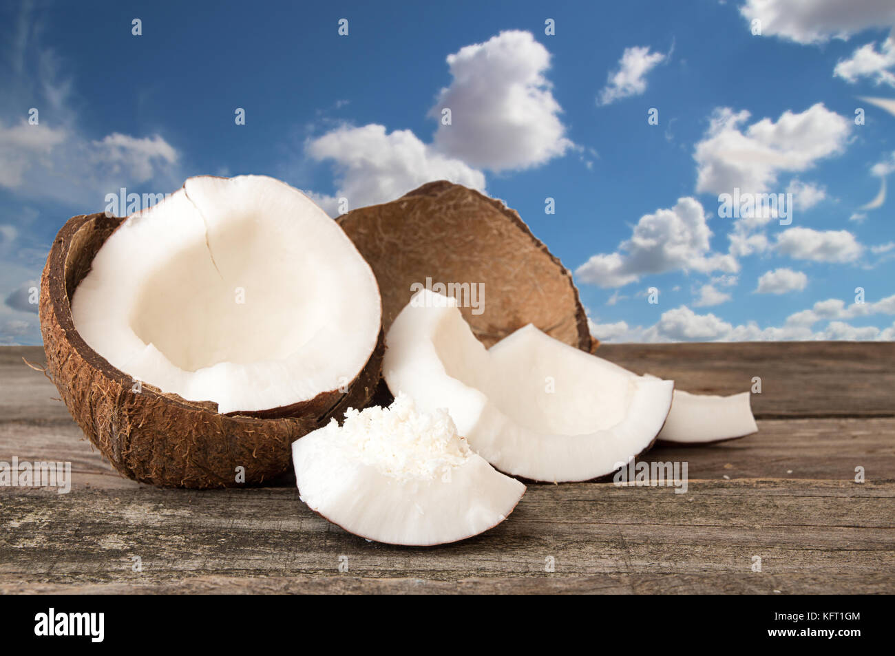 Halfs of coconut, pieces of coconat, coconut flakes on blue cloudy sky ...