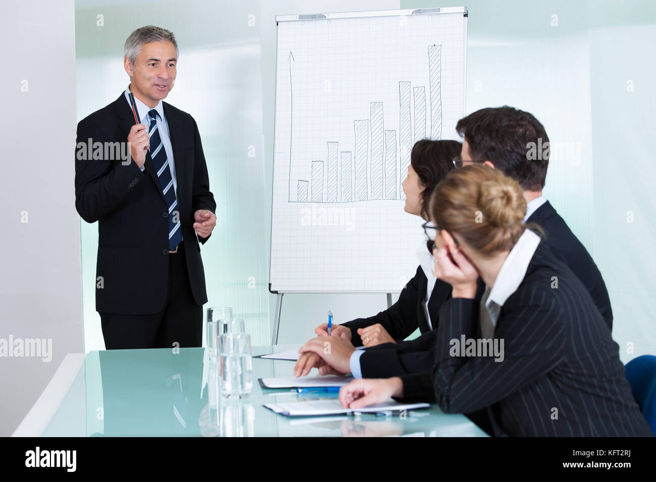 A senior business executive delivering a presentation to his colleagues ...