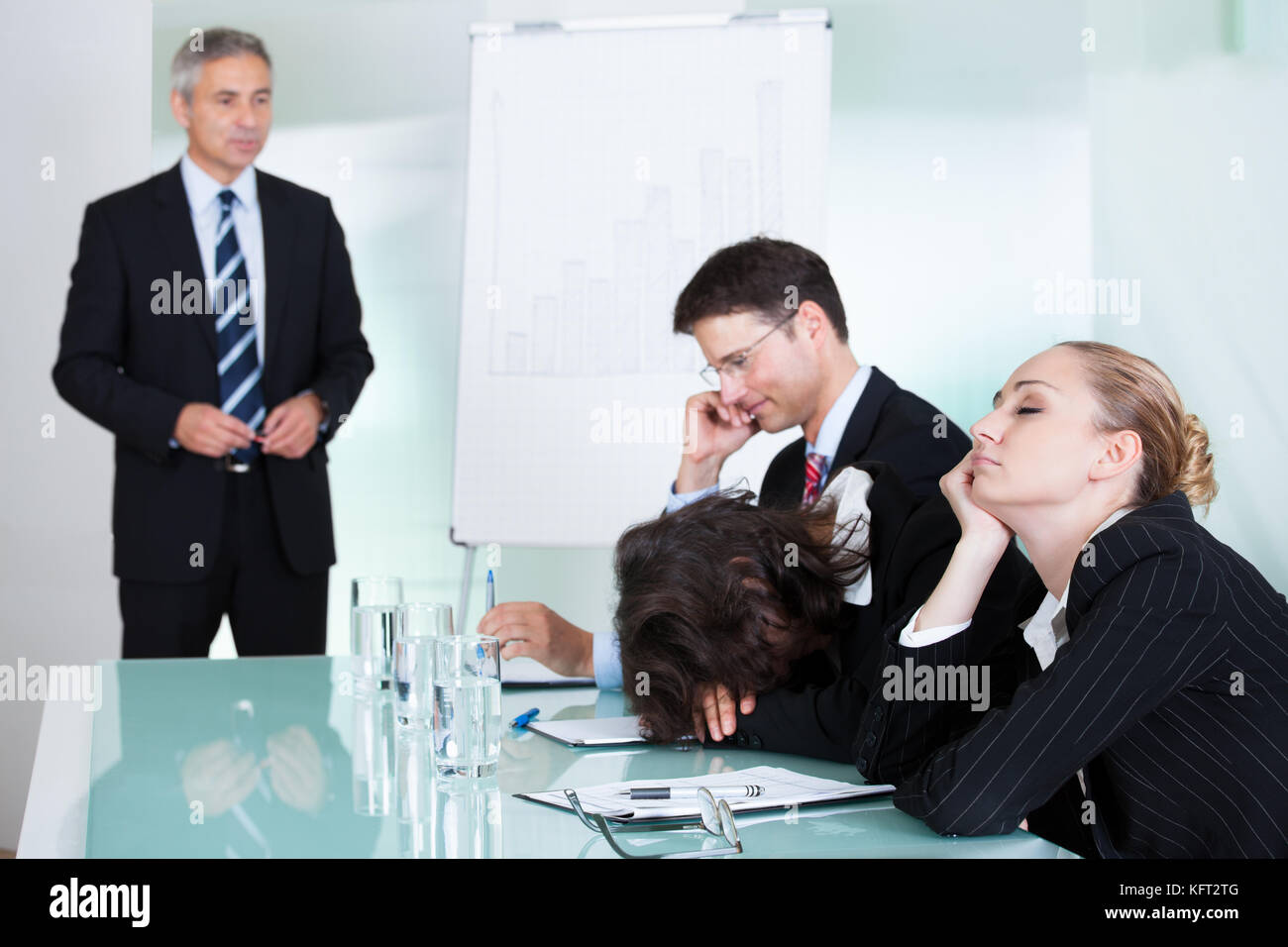 Bored businesswoman sleeping in a meeting as her colleague who is ...