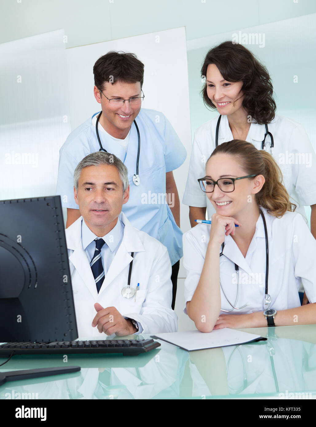 Doctors having a meeting seated at a table in front of a computer ...