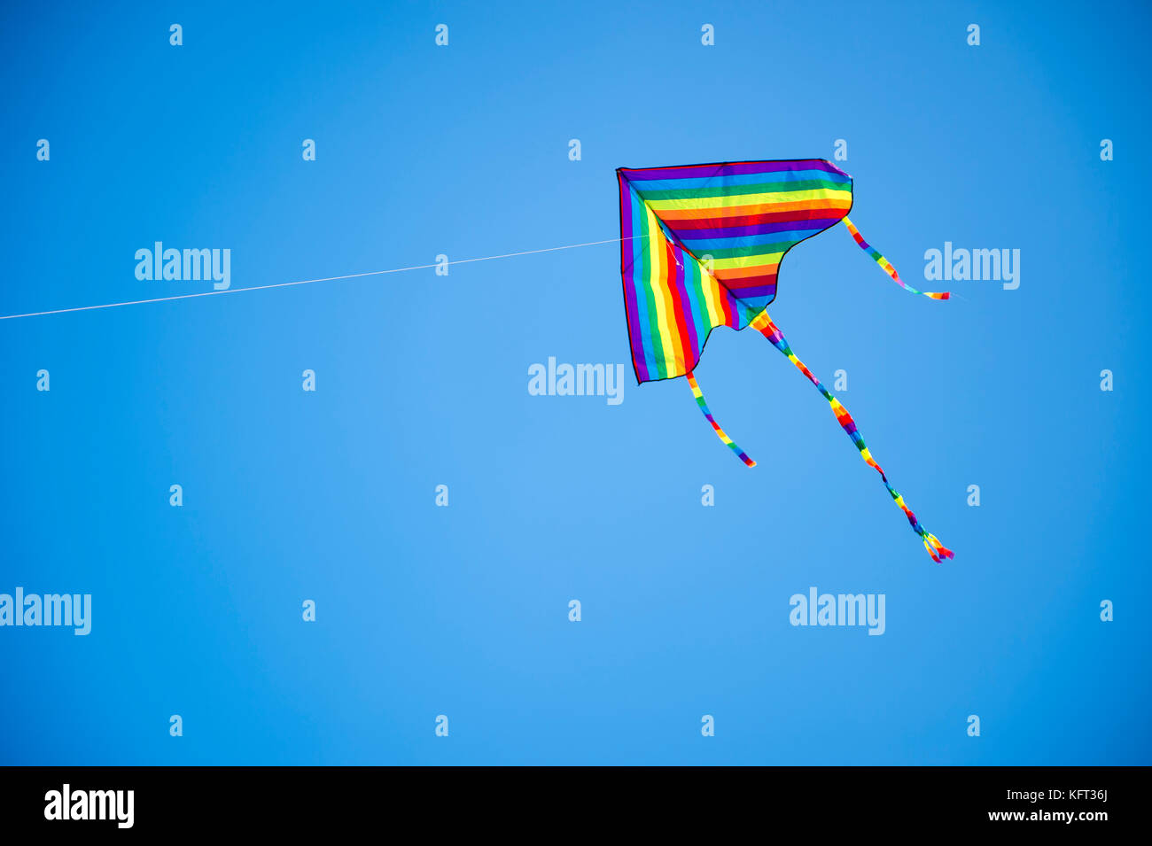 Colorful rainbow striped kite flying in a clear blue sky Stock Photo ...