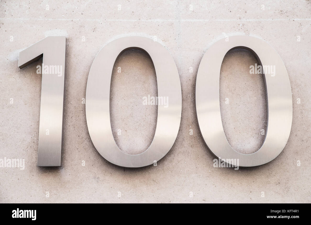 The Number 100 displayed on a stone wall Stock Photo - Alamy
