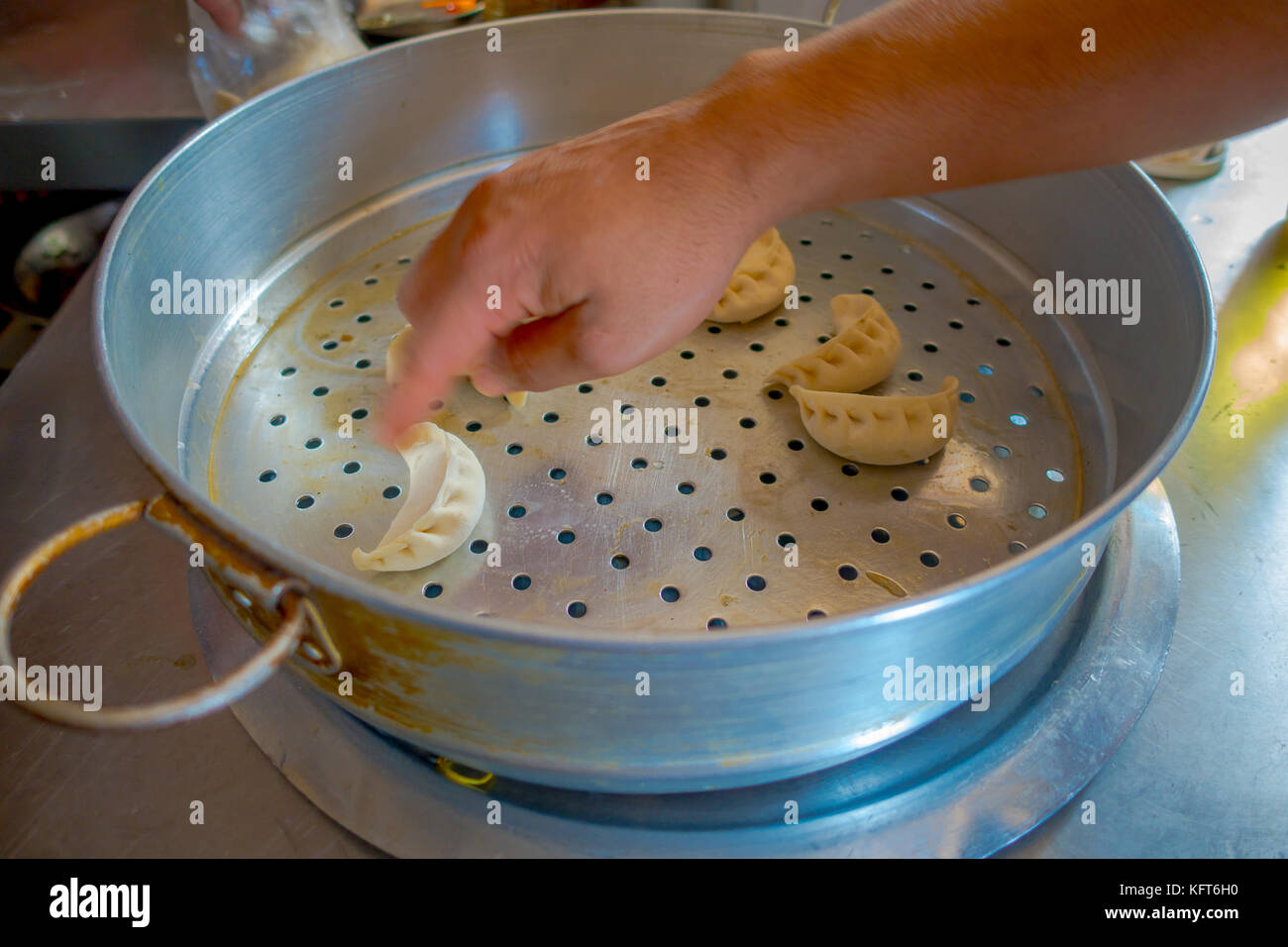Person cooking a momo food over a metallic tray in the kitchen, type of ...