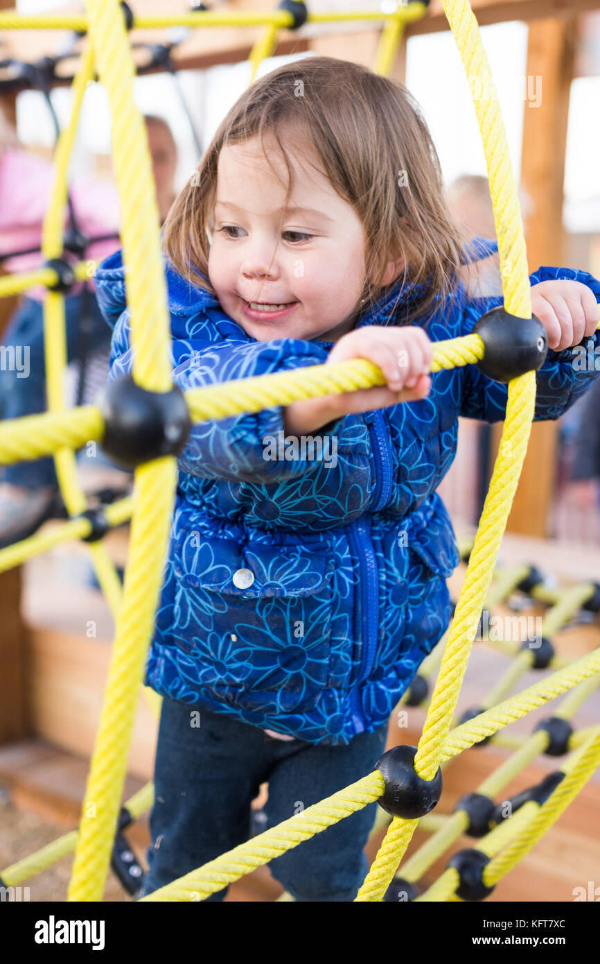 Little girl plays on yellow rope bridge on jungle gym Stock Photo - Alamy