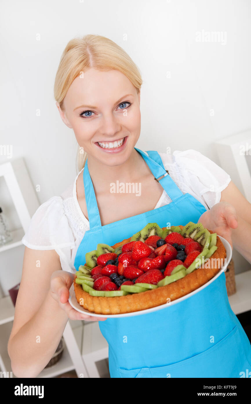 Beautiful young woman holding self-made cake in the kitchen Stock Photo ...