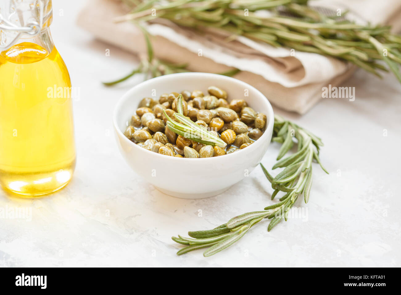 Capers, olive oil and rosemary on a light background, Italian ...