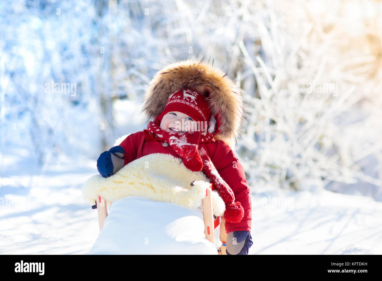 Sled and snow fun for kids. Baby sledding in snowy winter park. Little ...