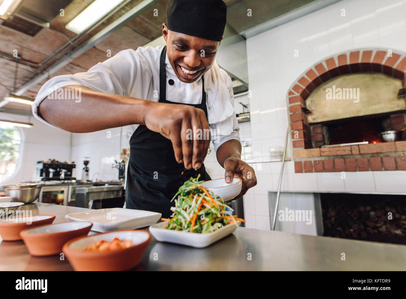 Male chef preparing salad in kitchen. Gourmet chef making delicious ...