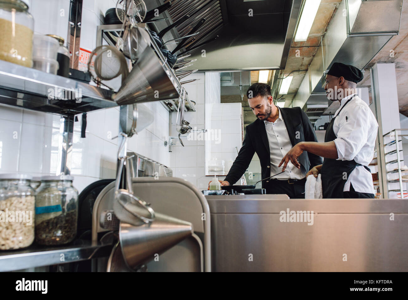 Restaurant owner with chef in kitchen. Cook talking with manager at ...