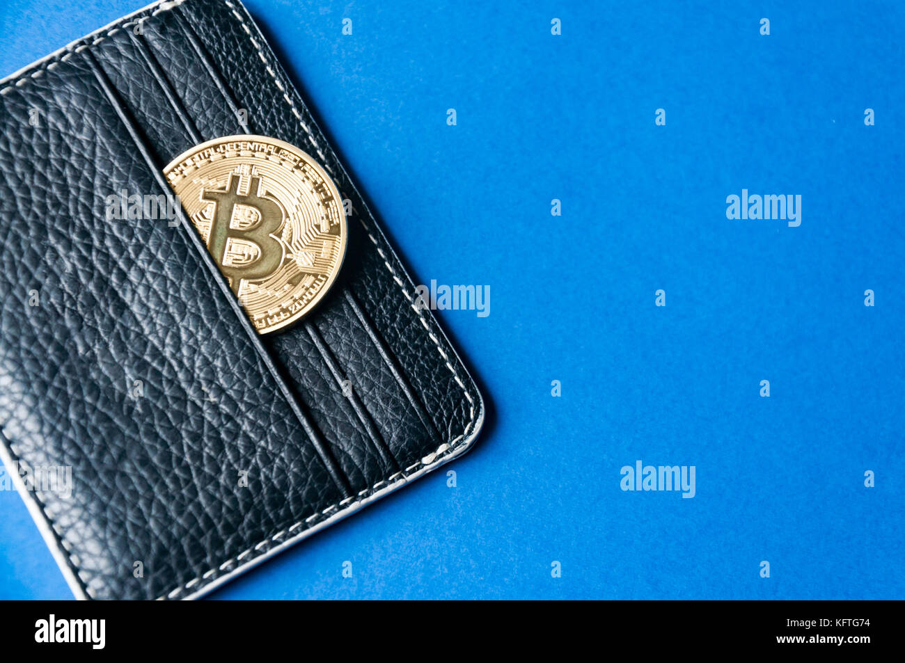 Black leather wallet on a blue background with several gold and silver ...
