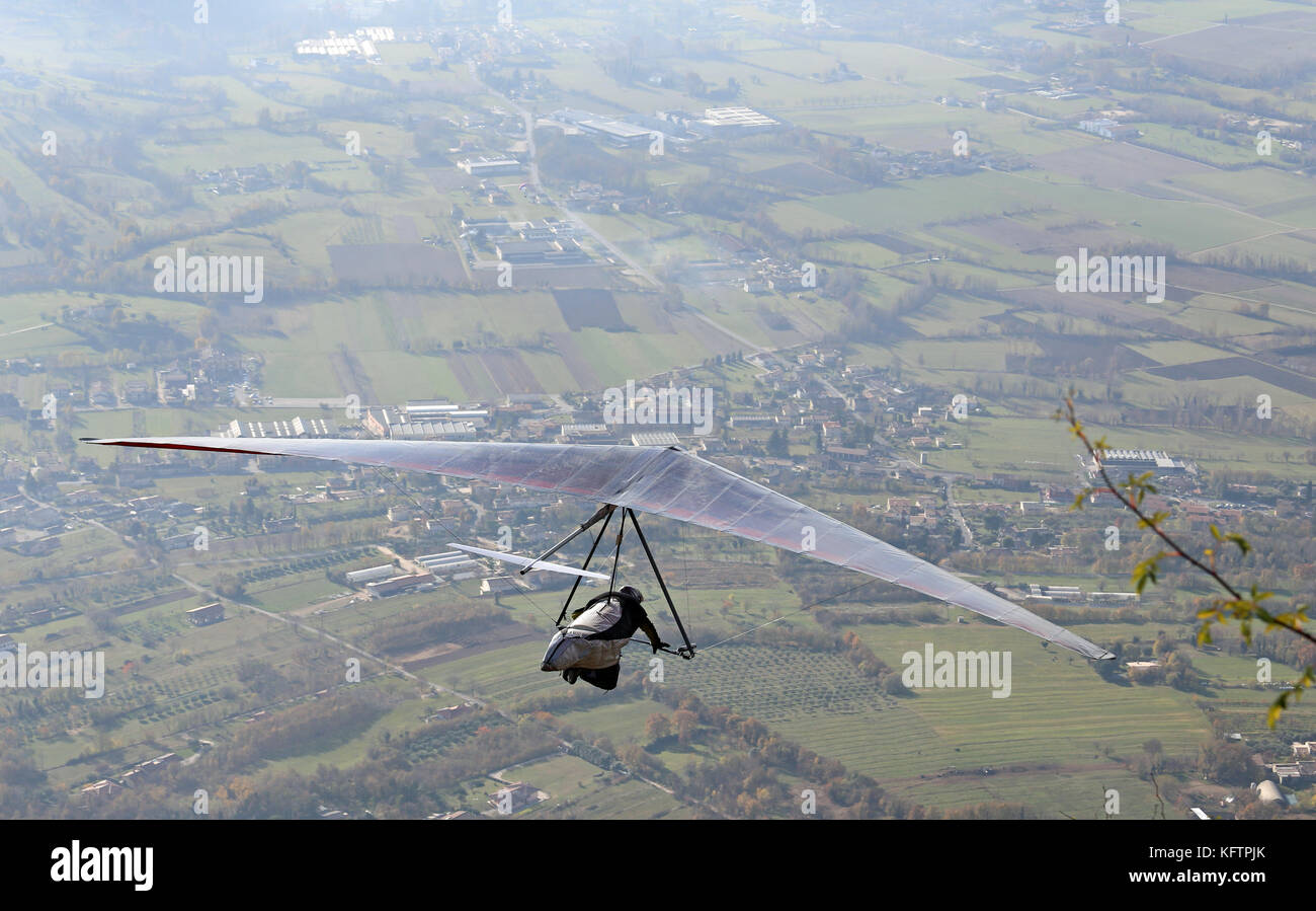man flying high with his hang glider above the plain. This is extreme ...