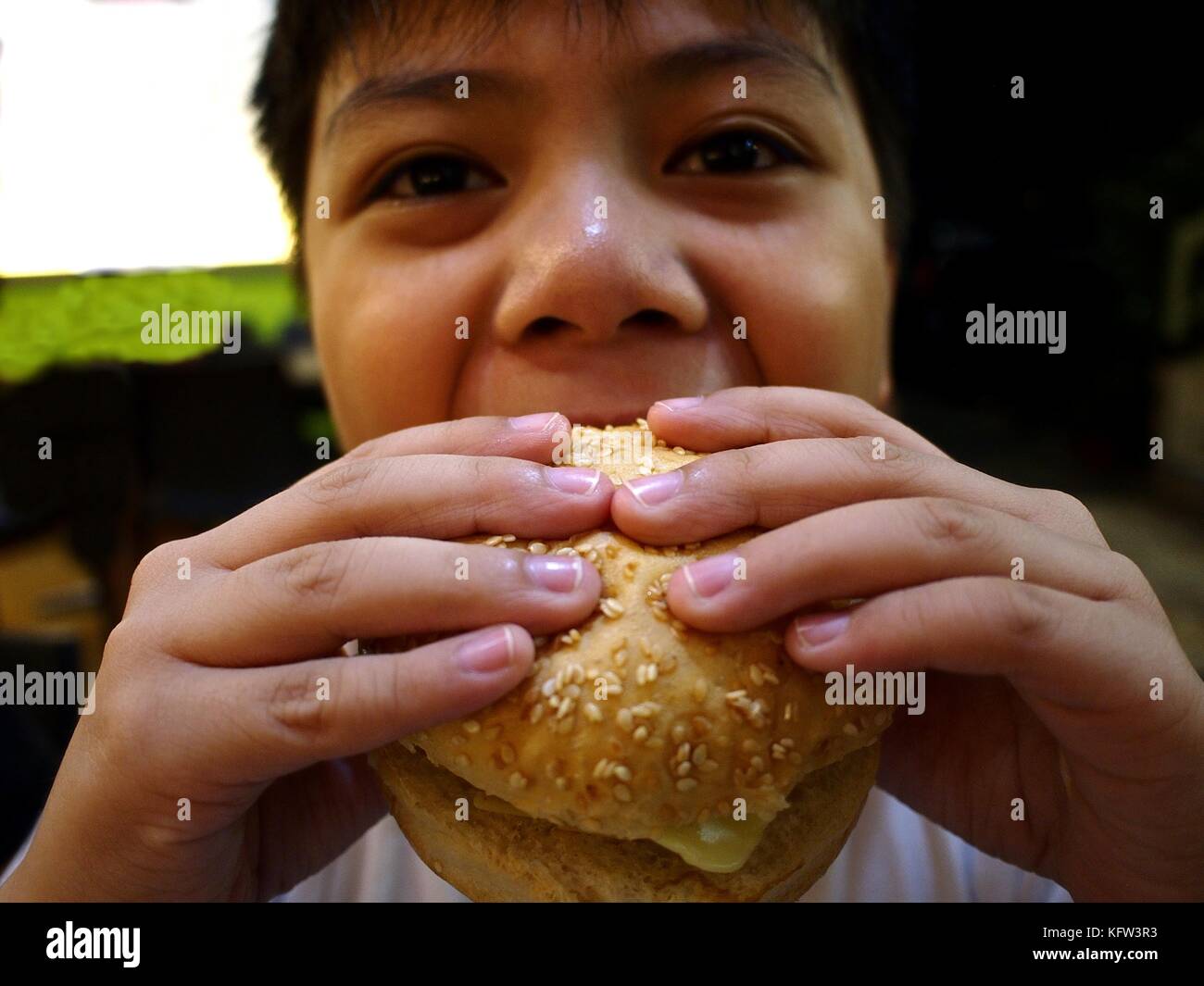 Photo of a young boy eating a hamburger Stock Photo - Alamy