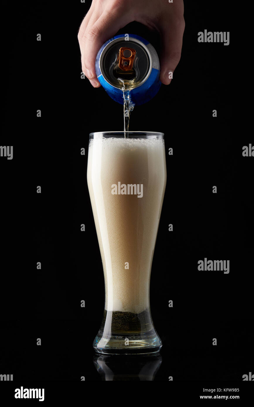 Pouring Beer From Metal Glass Into Tall Glass Isolated On Black