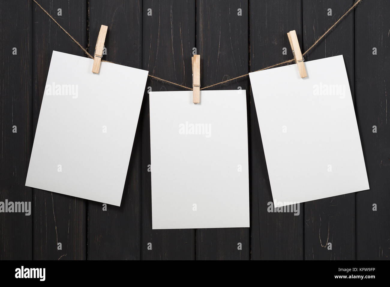 Three blank white paper cards hanging attach to rope with clothes pins ...