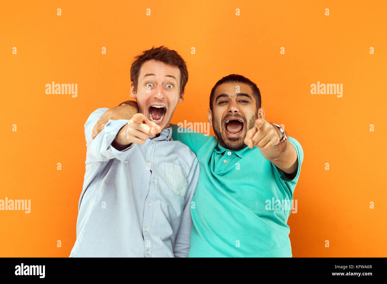 Closeup. Two happiness friends hugging each other, pointing finger and ...