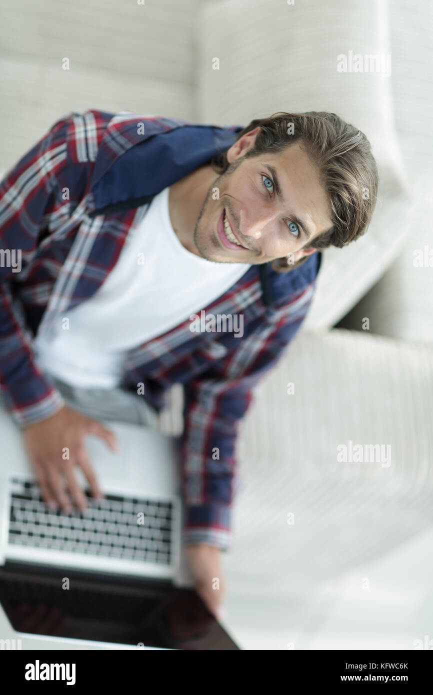 close-up. young man working on laptop and looking at camera. view from ...