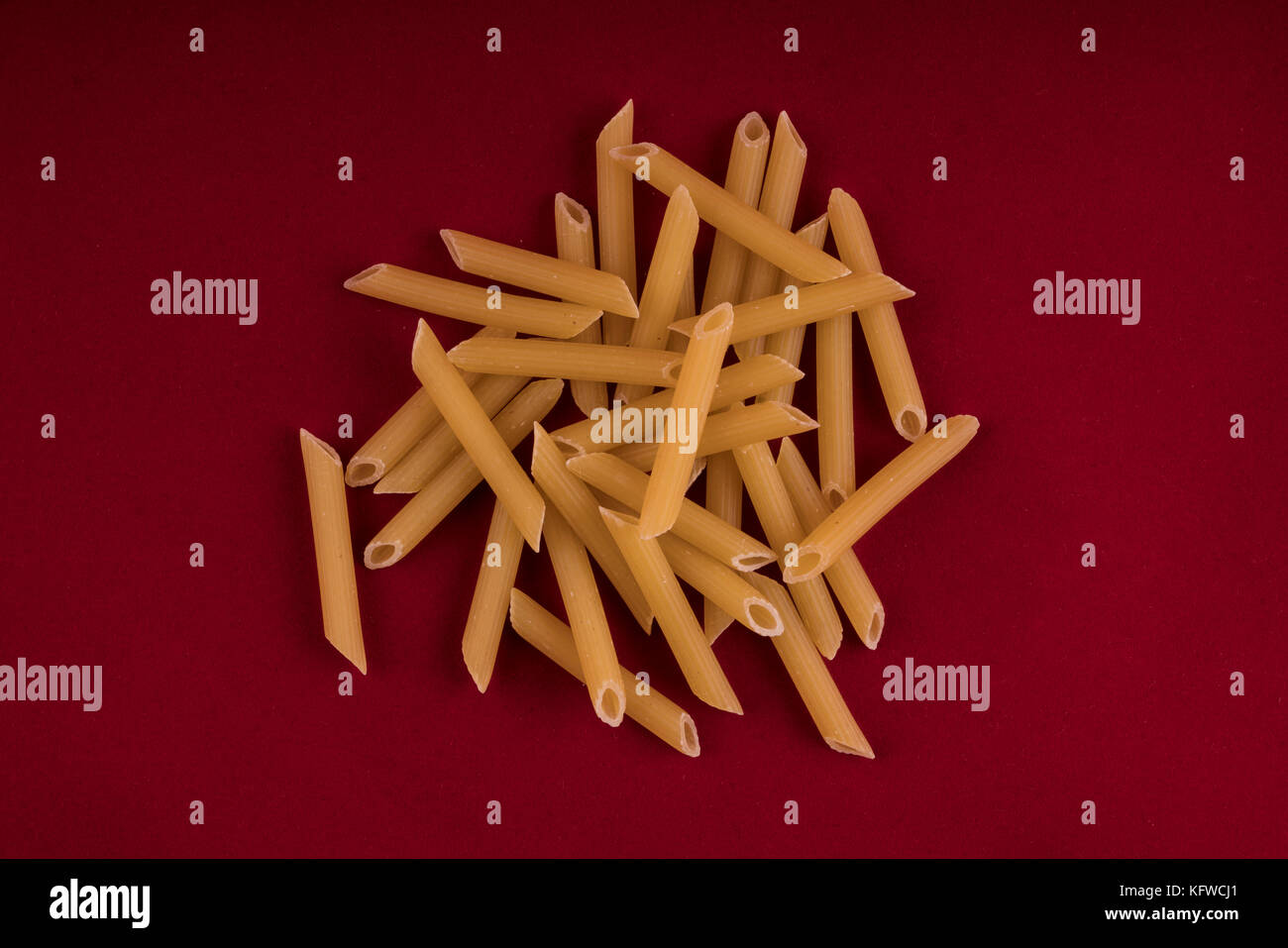 Italian rigatoni pasta on a red background Stock Photo - Alamy