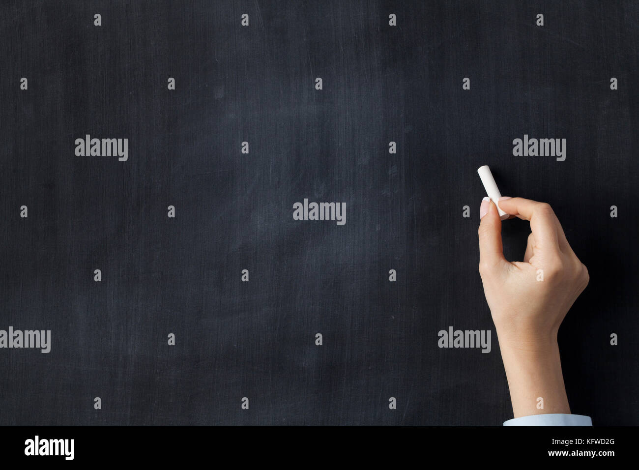 Close up of hand holding chalk on blank chalkboard Stock Photo - Alamy