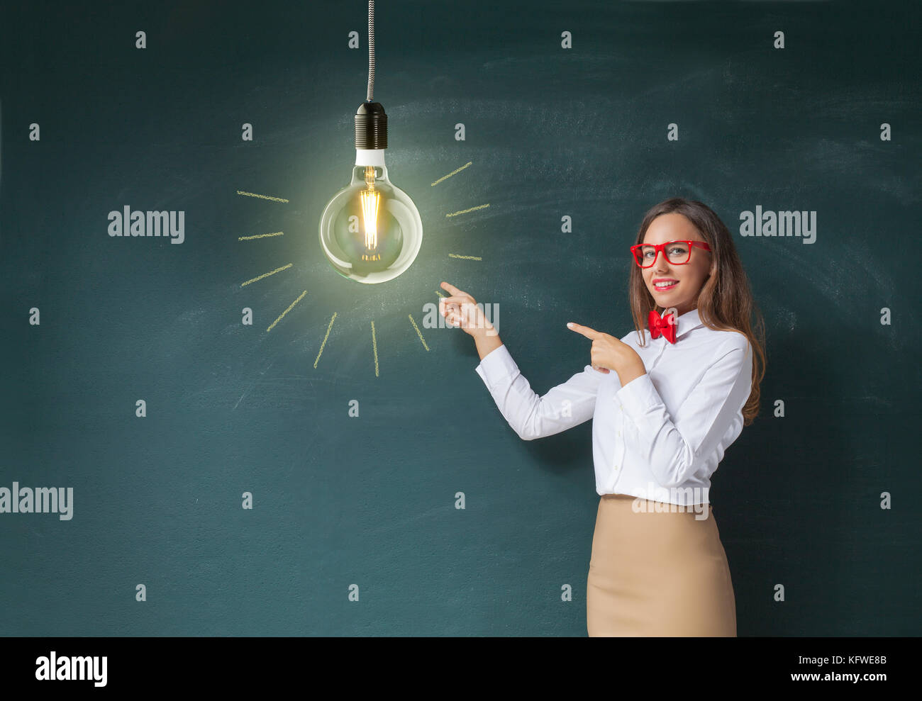 Young teacher pointing light bulb on blackboard background Stock Photo ...