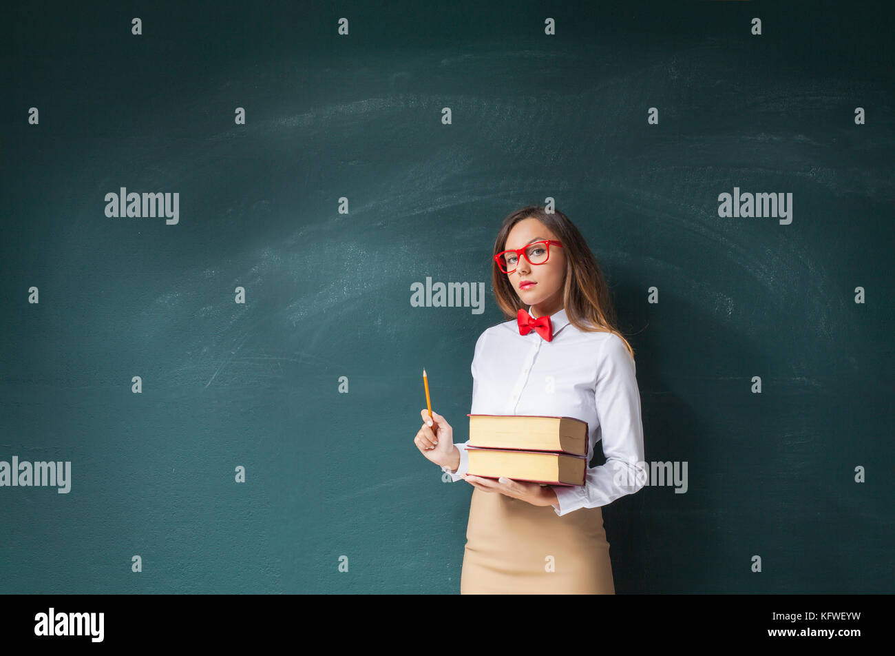 Serious young teacher standing near blackboard Stock Photo - Alamy