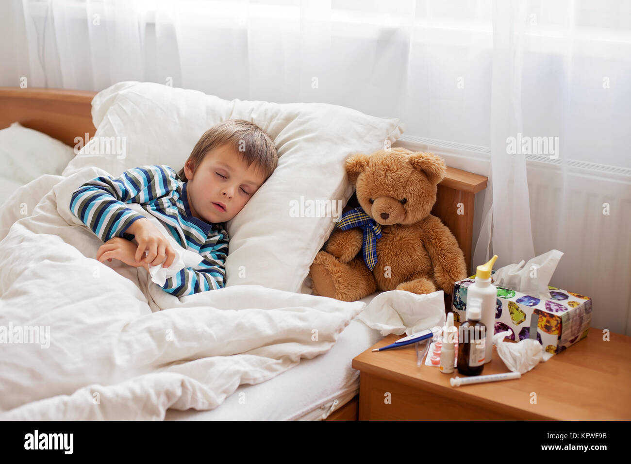 Sick child boy lying in bed with a fever, resting at home Stock Photo ...