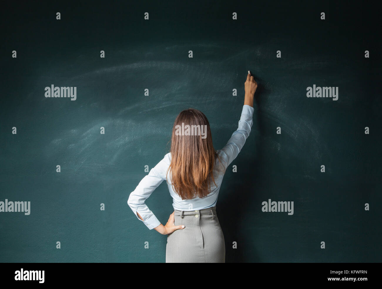 Back view of a businesswoman about to write something on a blackboard ...