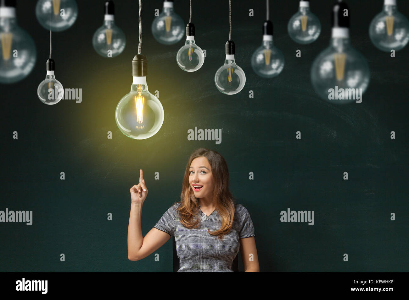 Young student pointing light bulb on blackboard background Stock Photo ...