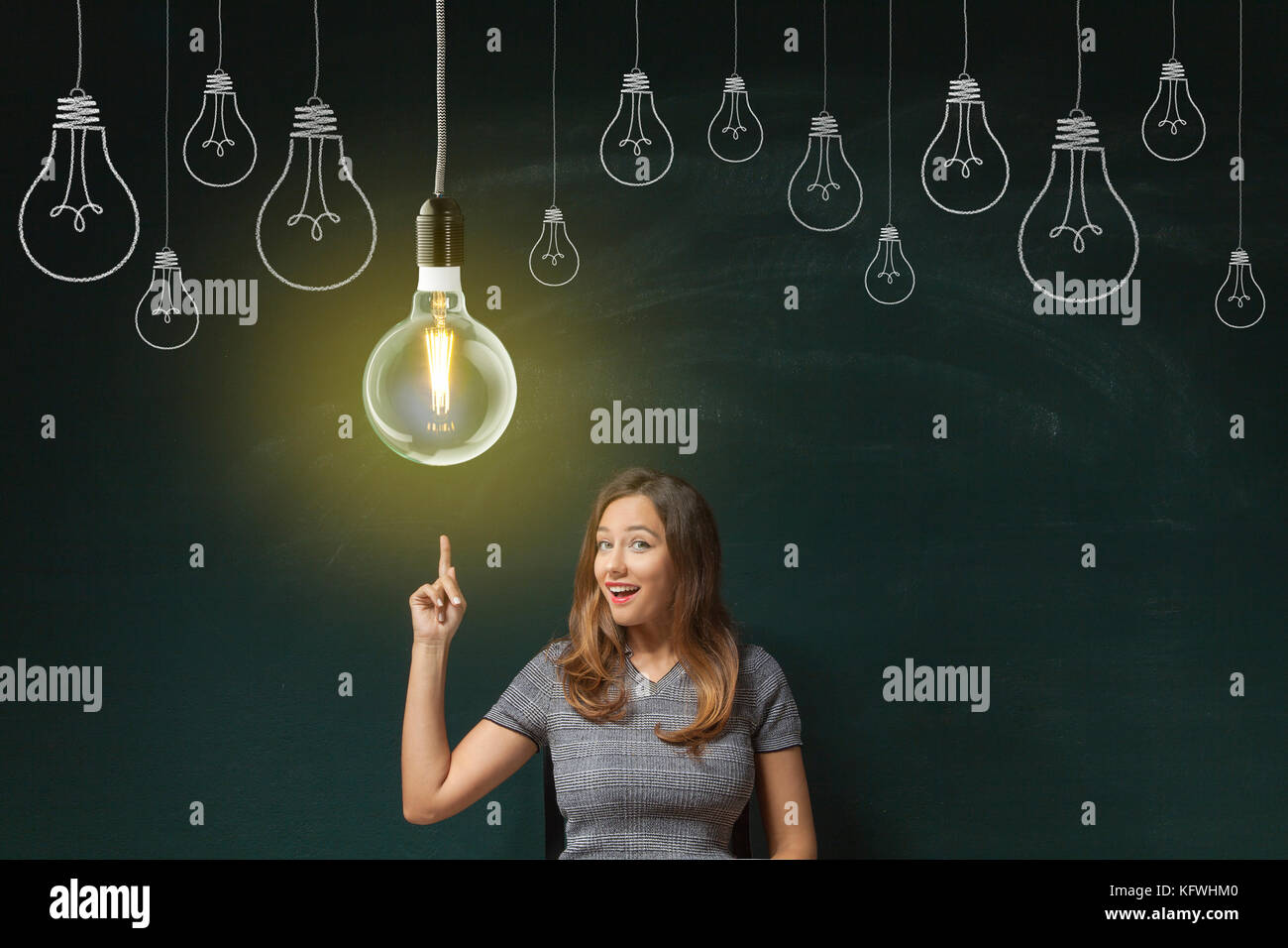Young student pointing light bulb on blackboard background Stock Photo ...