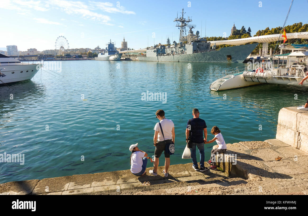 Family at Muelle uno, quay in Port of Malaga, with two warships in ...