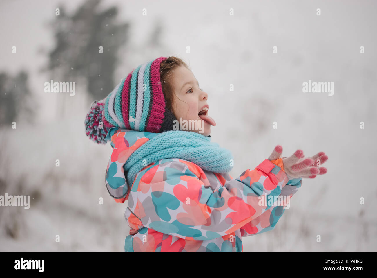 little girl catching snowflakes in winter park Stock Photo - Alamy