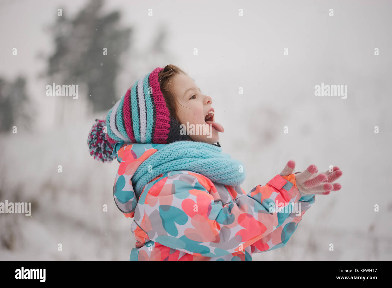 little girl catching snowflakes in winter park Stock Photo - Alamy
