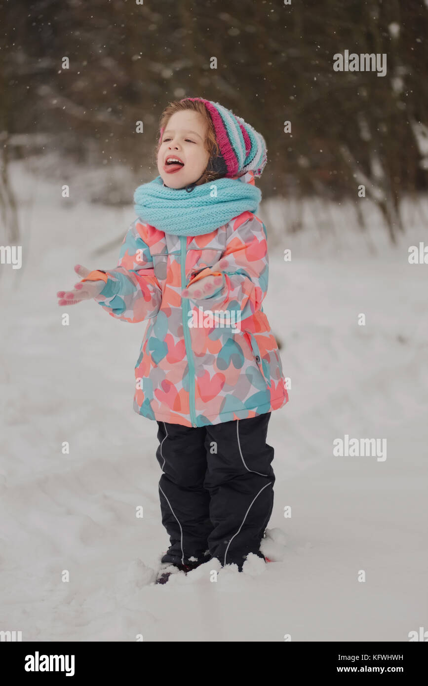 little girl catching snowflakes in winter park Stock Photo - Alamy