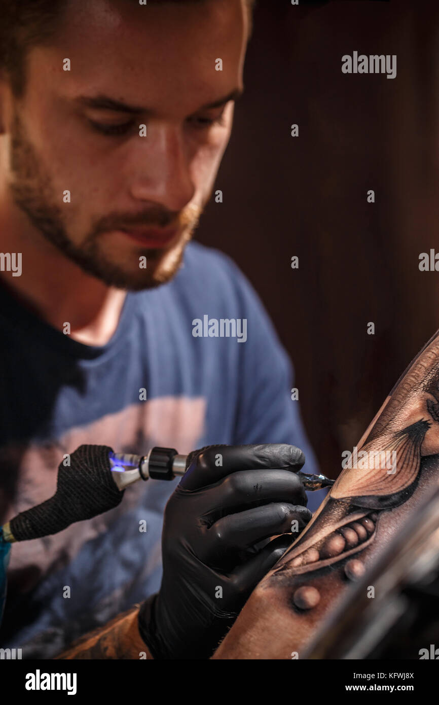Professional tattoo artist makes a tattoo on a young man's hand Stock ...