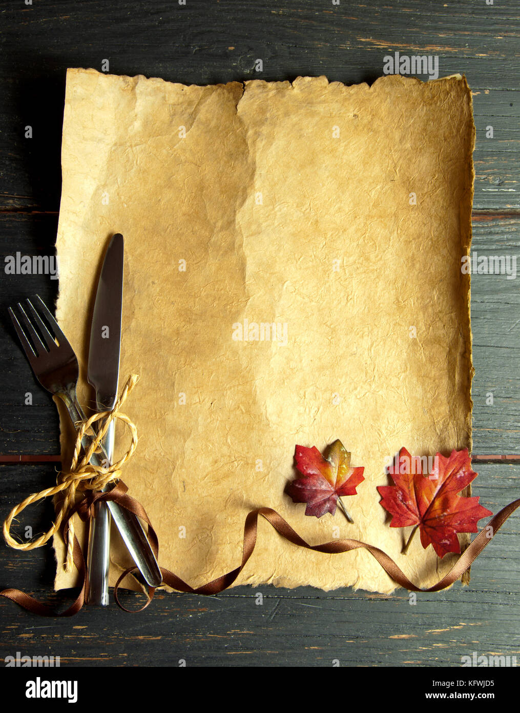 Empty paper scroll with fork and knife tied with ribbon bow and autumn ...