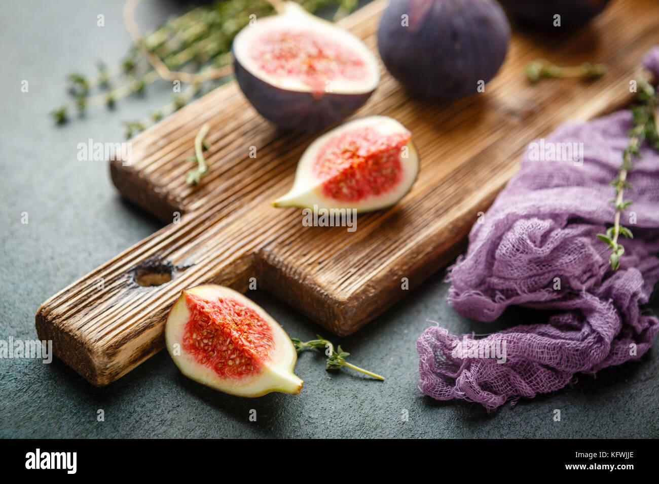 Juicy fresh whole fig fruits and one cut figs on wooden cutting board ...