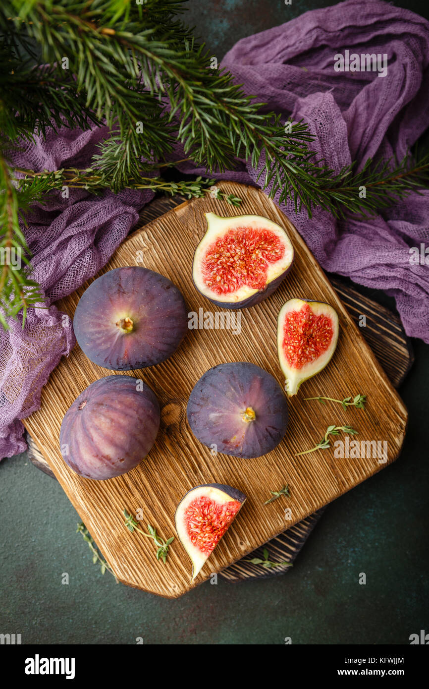 Juicy fresh whole fig fruits and one cut figs on wooden cutting board ...