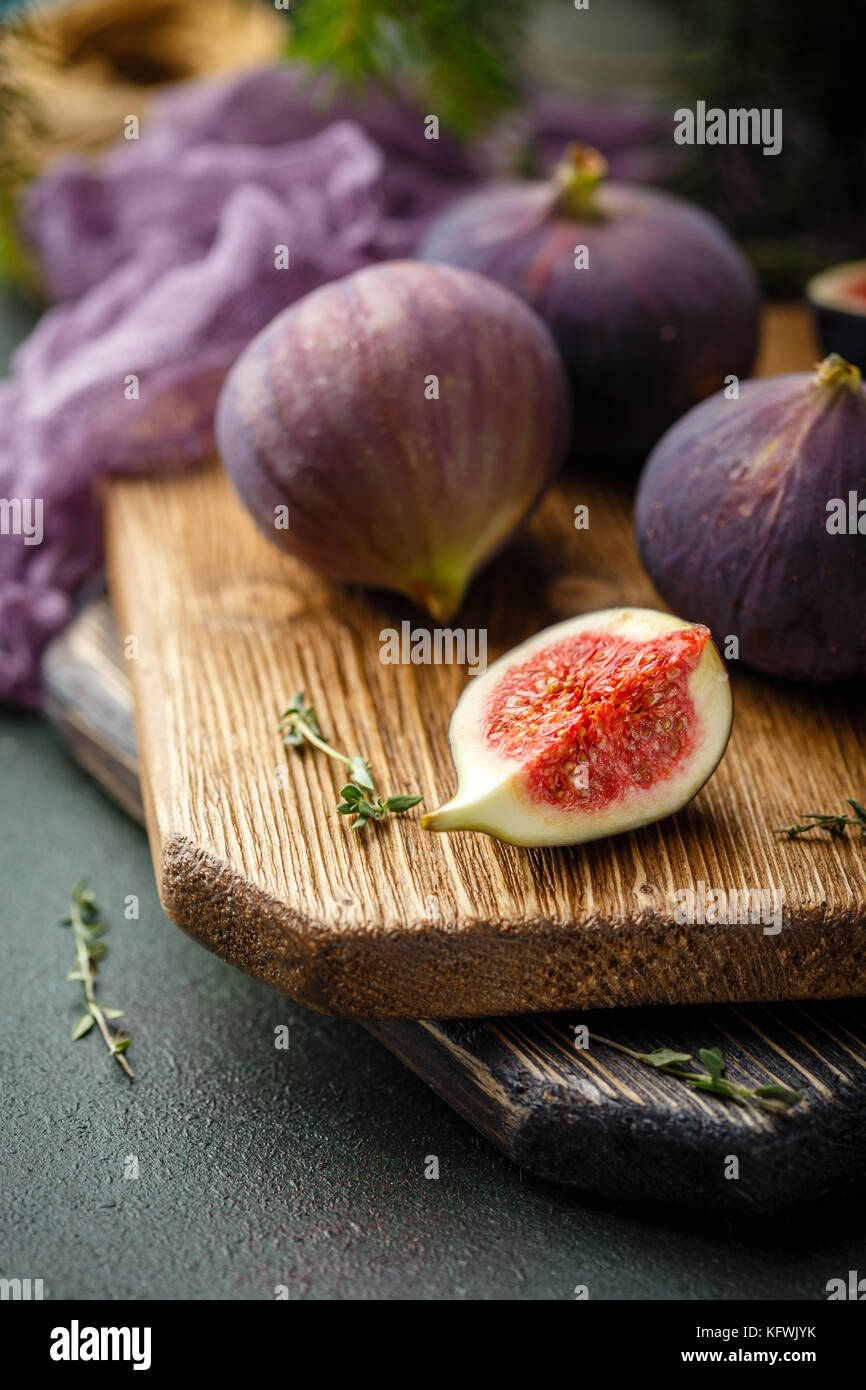 Juicy fresh whole fig fruits and one cut figs on wooden cutting board ...