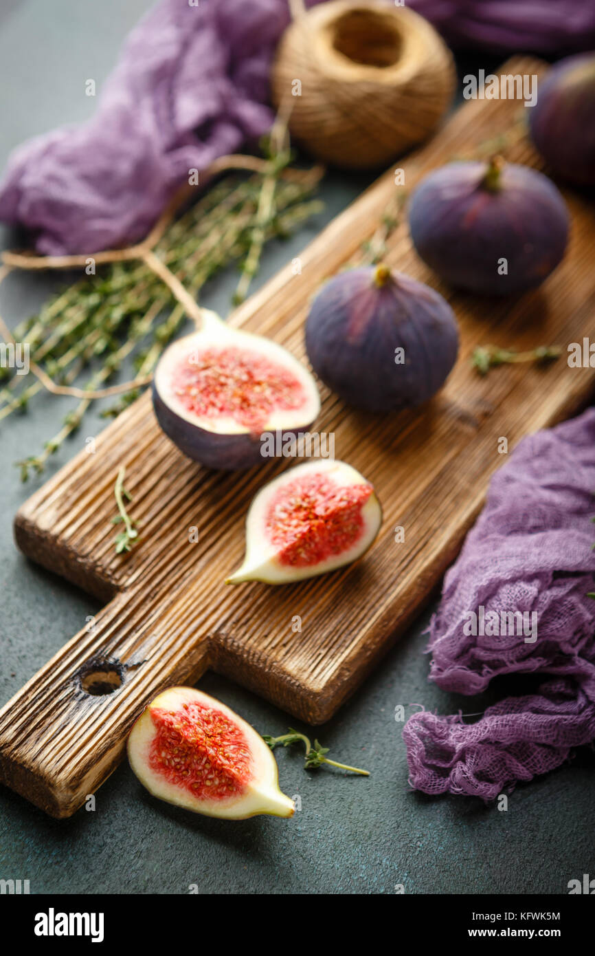 Juicy fresh whole fig fruits and one cut figs on wooden cutting board ...