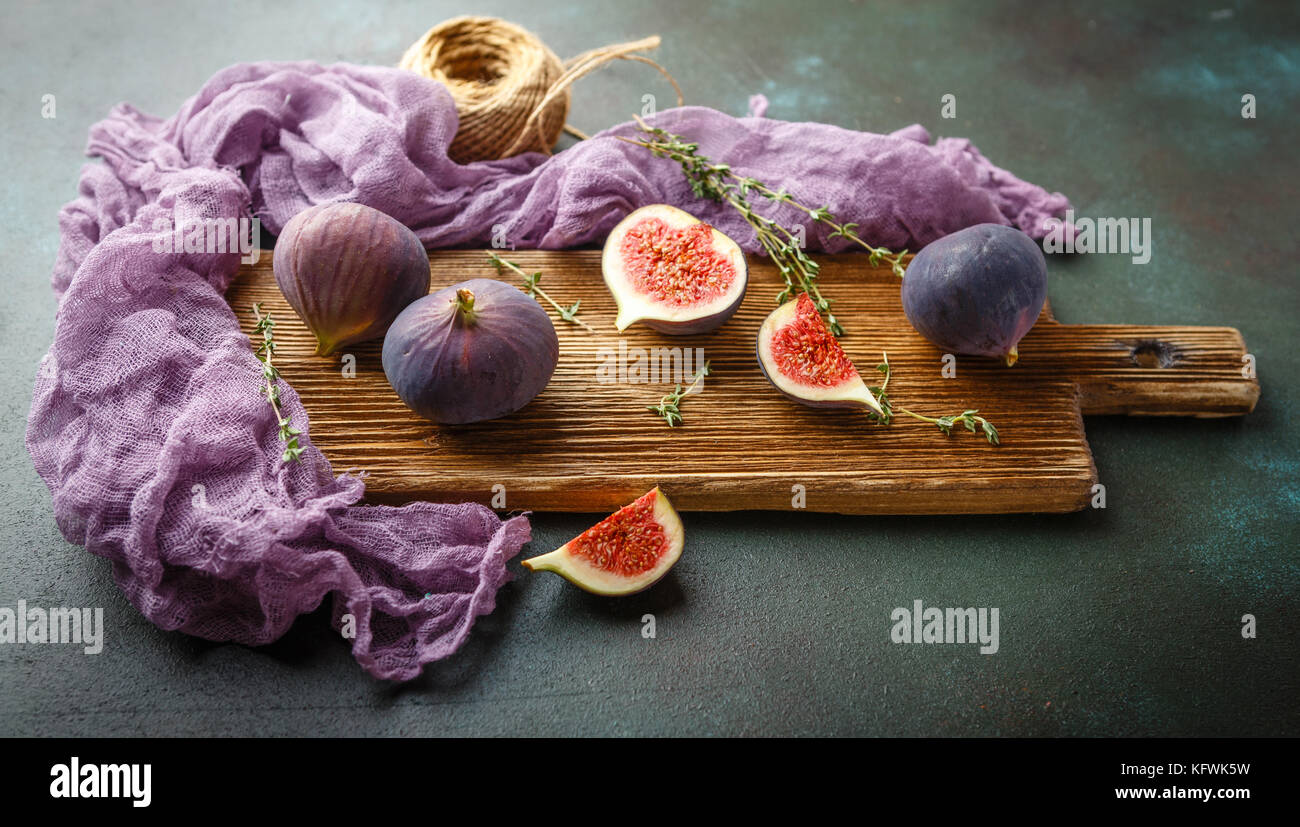 Juicy fresh whole fig fruits and one cut figs on wooden cutting board ...