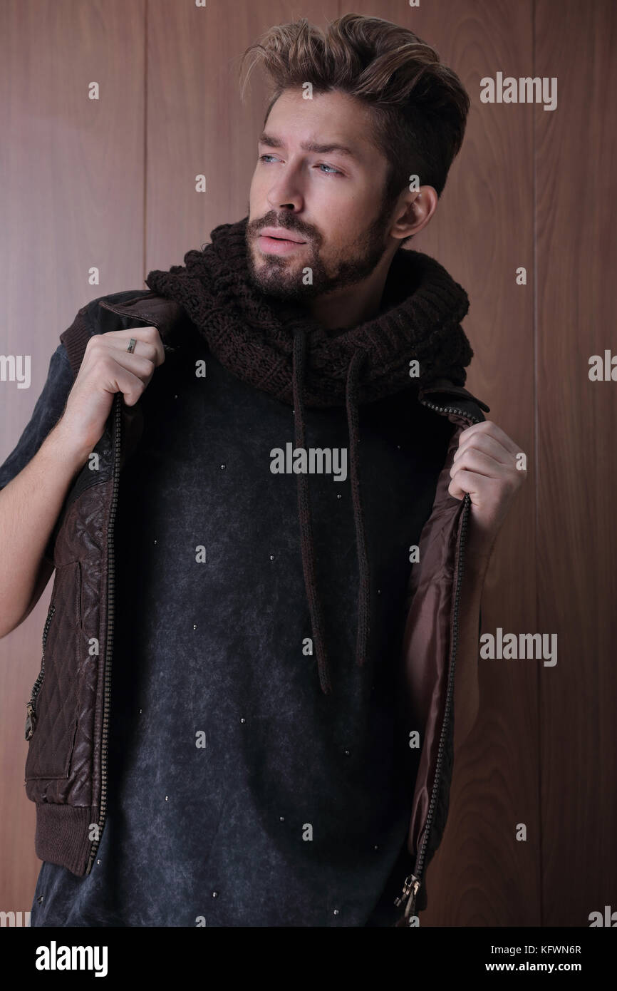 angry man pulling at the gates of his leather jacket against the studio ...