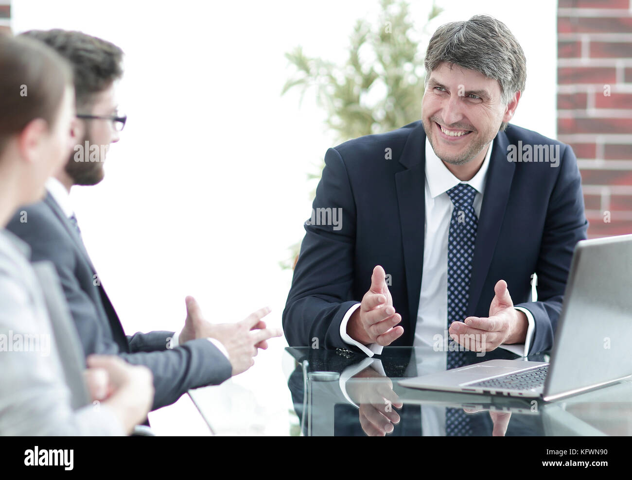 positive manager with his team sitting at the table Stock Photo - Alamy